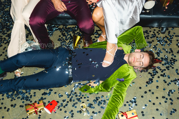 handsome and drunk man sleeping on floor near friends and confetti ...