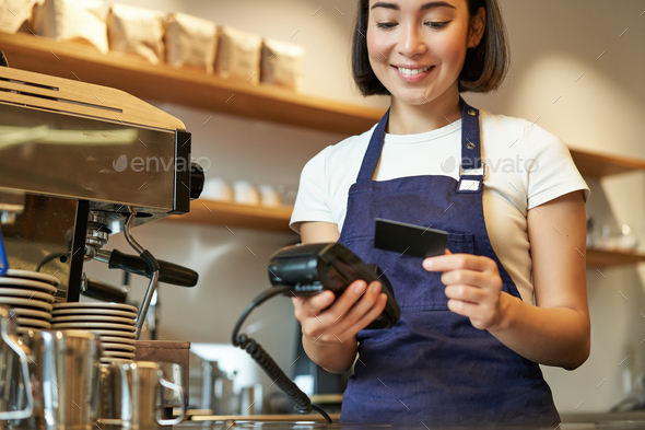 Beautiful smiling asian girl, barista insert client credit card in POS ...