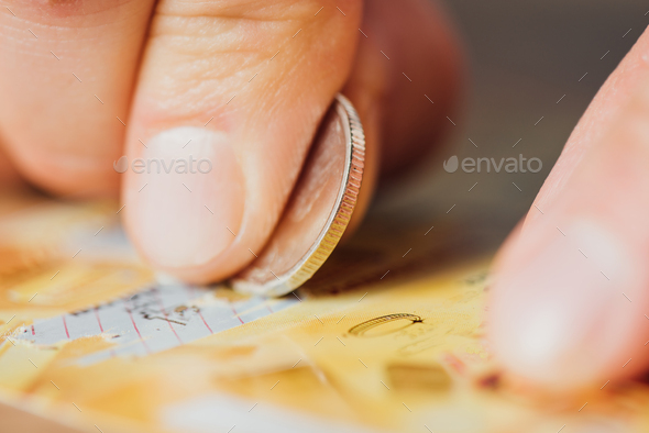 close up view of silver coin in hand of gambler scratching lottery ...