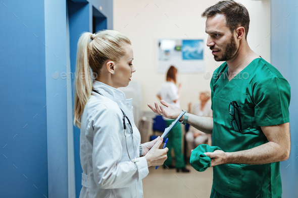 Surgeon talking to nurse while standing in a hallway at the hospital ...