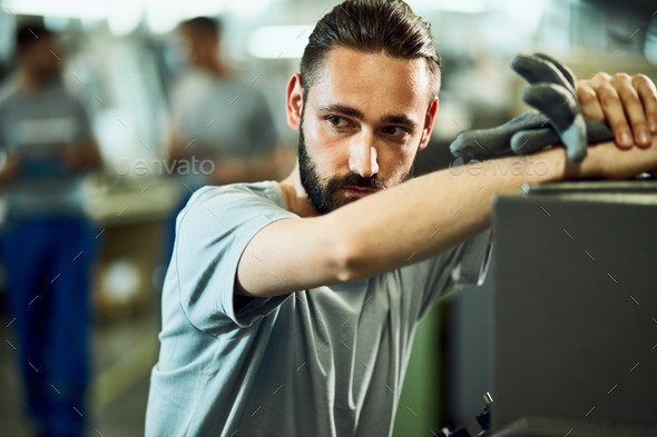 Distraught factory worker leaning on CNC machine while working in ...
