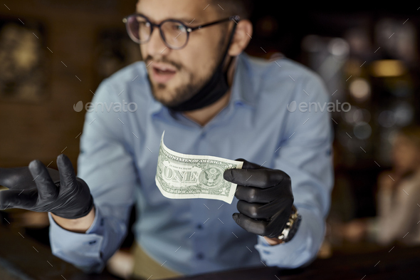 Close-up of dissatisfied waiter holding one dollar bill while working ...