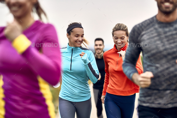 Happy athletic women having fun while jogging with group of people in ...