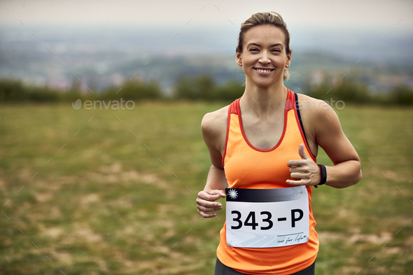 Happy female marathon runner in nature. Stock Photo by drazenphoto