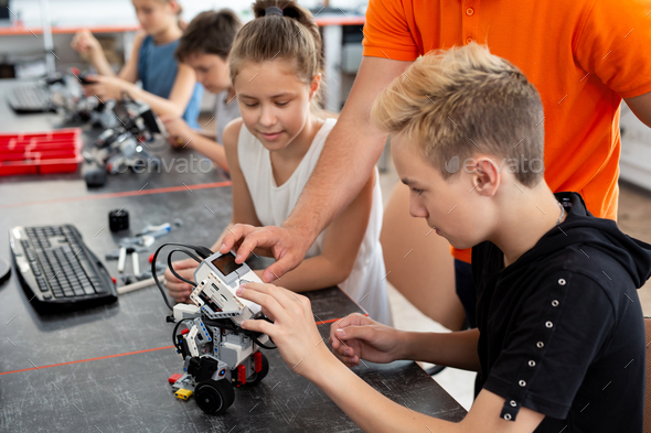 Kids working with teacher on their robot education project. Stock Photo ...