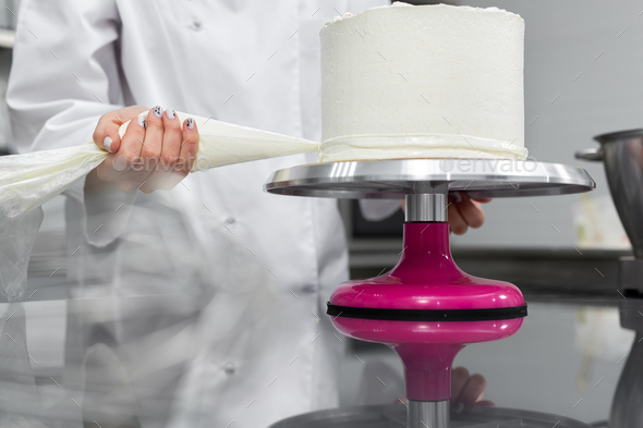 The pastry chef levels the cake with cream. Stock Photo by StudioPeace