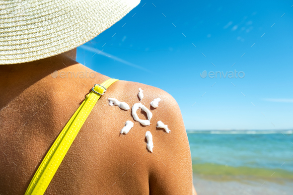 Back view of young woman tanning at the beach with sunscreen cream in ...