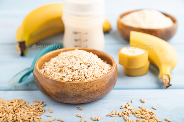 Powdered milk and oatmeal, banana baby food mix, on blue wooden, side ...