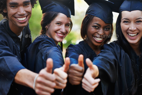 Get educated. A group of smiling college graduates giving the thumbs up ...