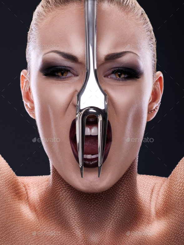 Snake Woman. Shot of a woman with a fork in front of her face imitating ...