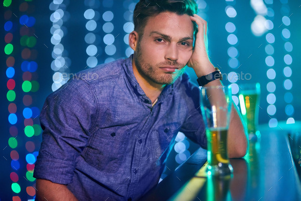 Portrait of a young man looking upset while sitting at the bar in a ...