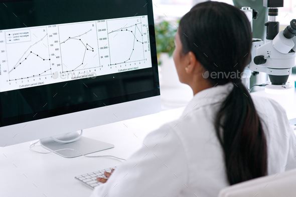 Rearview shot of an unrecognizable young female scientist working on her computer in the ...
