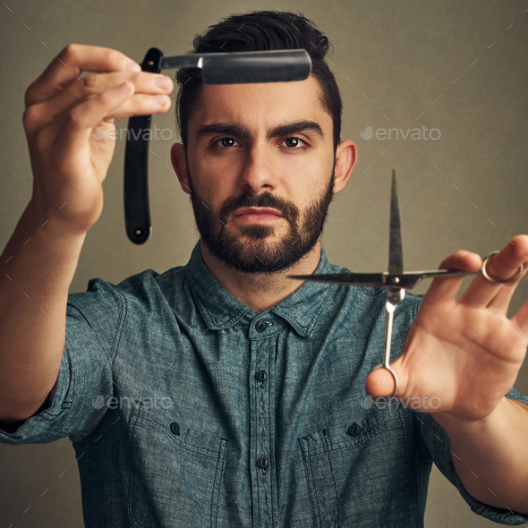 Studio shot of a handsome young man holding a straight razor and a ...
