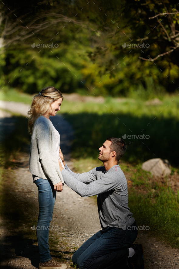 Shot of a man kneeling and touching his wifes stomach while enjoying a ...