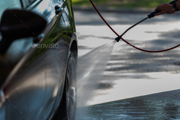 Car washing. Man cleaning automobile using high pressure jet water ...