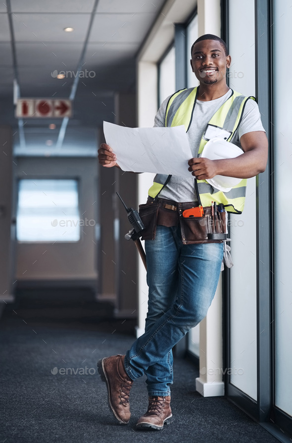 Shot of a handsome young contractor standing alone in a building and ...