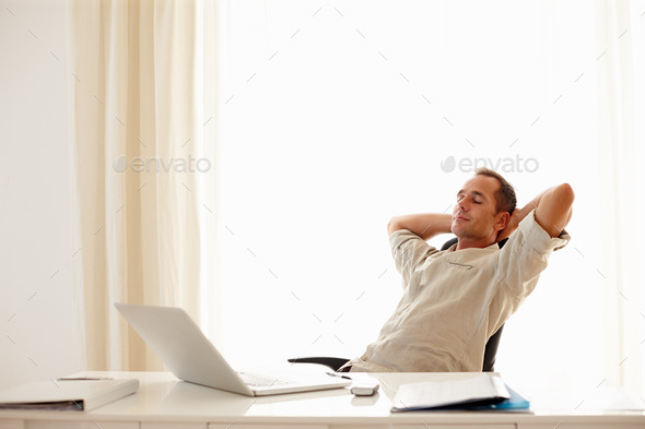 Kick back in-between deadlines. Businessman at work taking a minute to ...