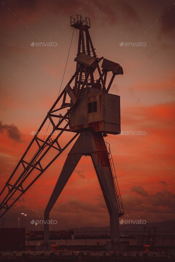 Vertical view of an old construction crane machine against the red ...