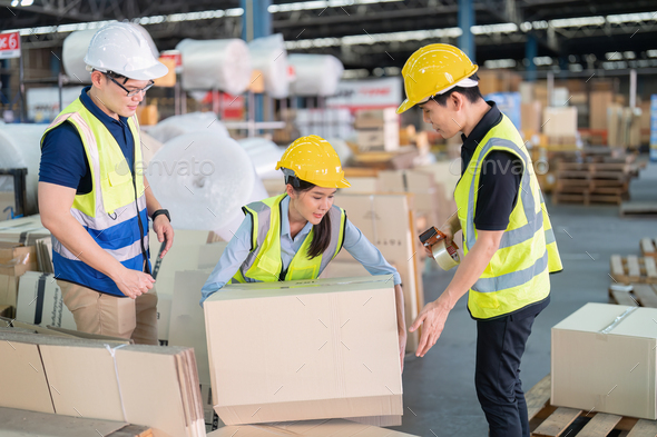 Staff in large storage warehouse together packing goods and carry ...
