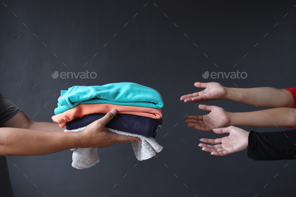 Hand giving stack of clothes Stock Photo by Queenmoonlite35 | PhotoDune