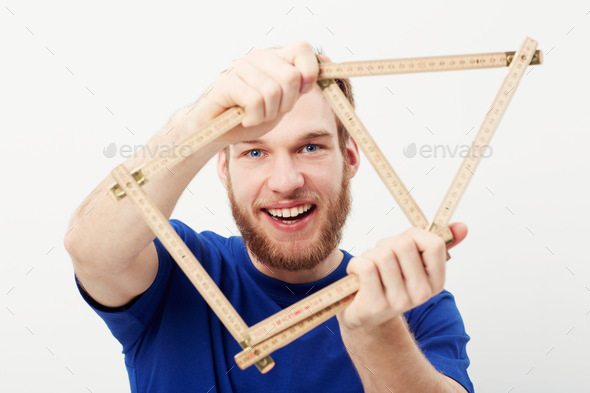 Portrait of a happy young man holding up a carpenters ruler in the ...
