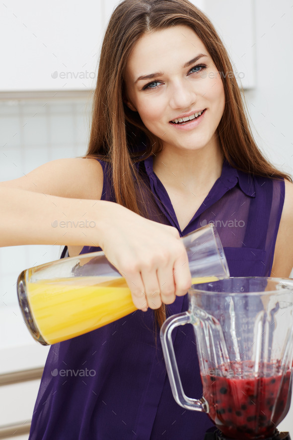 Portrait of a beautiful young woman making a healthy shake with her ...
