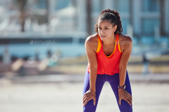 Shot of a sporty young woman taking a break after an intense workout ...