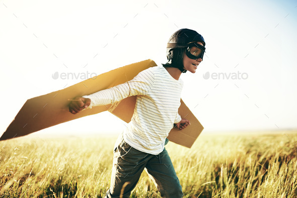 Shot of a young boy pretending to fly with a pair of cardboard wings in ...