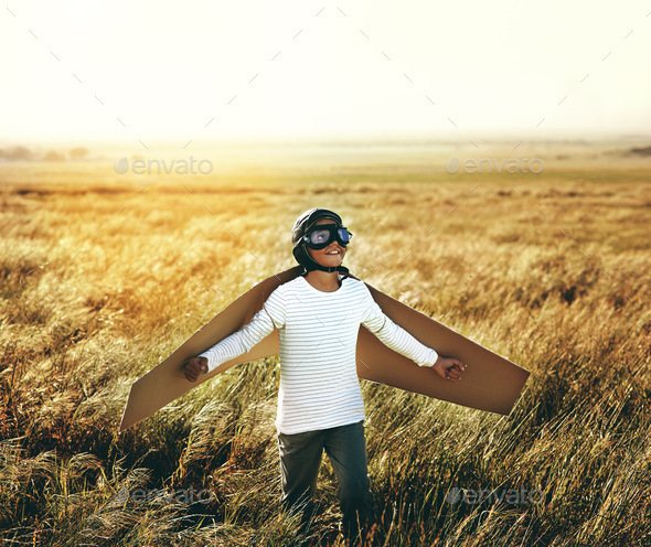 Shot of a young boy pretending to fly with a pair of cardboard wings in ...