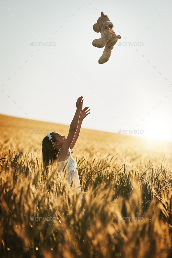 Up, up and away. Shot of a cute little girl playing with her teddybear in a cornfield. Stock ...