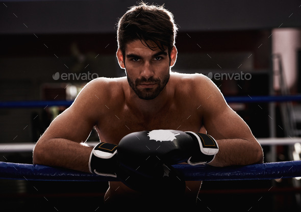 This ring is mone. Portrait of a young boxer leaning on the ropes of a ...