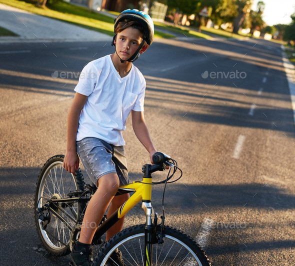 Cycling through his block. Shot of a young boy riding his bicycle ...