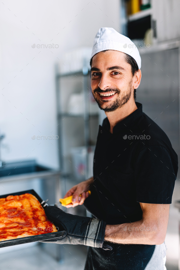 Italian chef pizzaiolo putting pizza to oven in restaurant kitchen ...