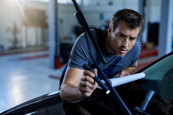 Car mechanic using flashlight while working at auto repair shop. Stock ...