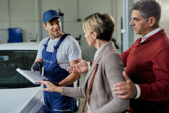 Happy mechanic and his customers going through check list in auto ...