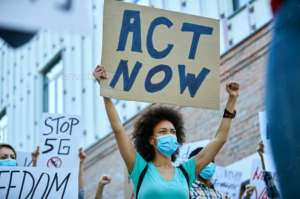 Black woman with face mask protesting with crowd of people during ...