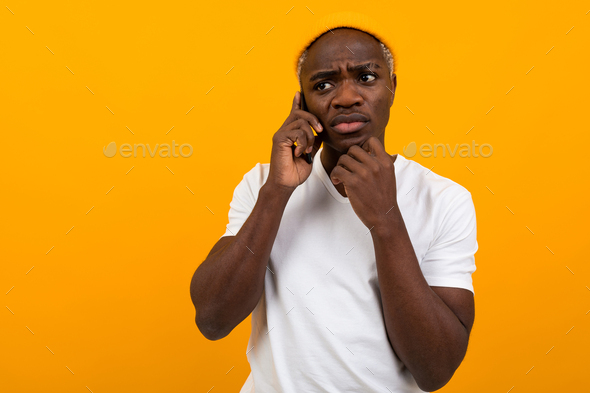 handsome pensive serious american man talking on the phone on a yellow ...