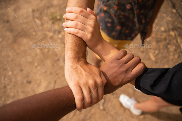Three hands of different ethnicities grasp each other and form a ...