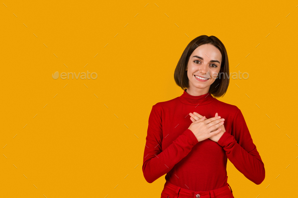 Thankful young woman holding hands over chest Stock Photo by Prostock ...