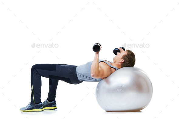 Keeping toned. Shot of a man balancing on an exercise ball lifting ...