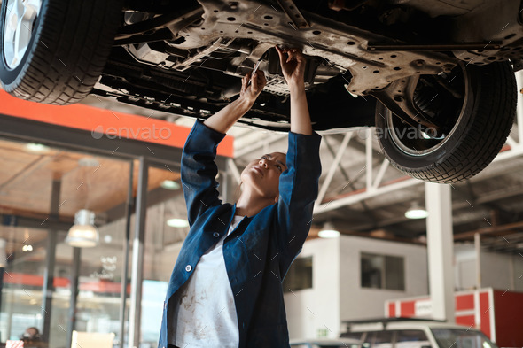 Shot of a female mechanic working under a lifted car Stock Photo by ...