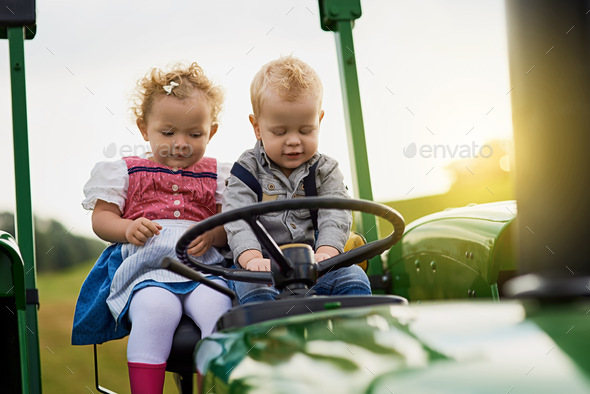Shot of two adorable children riding a tractor together on a farm Stock ...