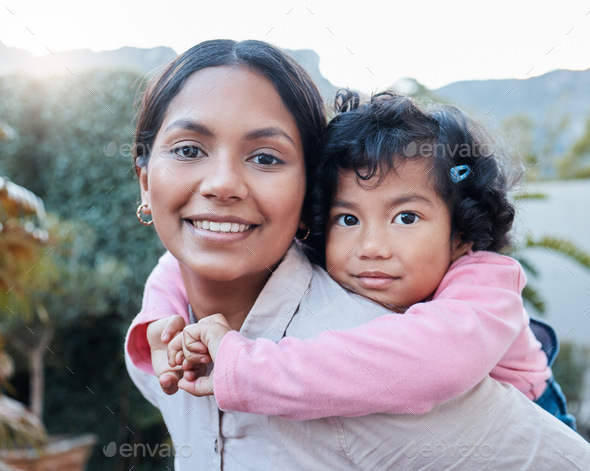 Shot of a woman carrying her daughter on her back while standing ...