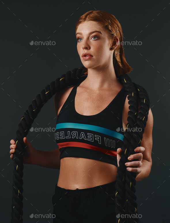 Studio shot of a sporty young woman posing with a battle rope against a ...