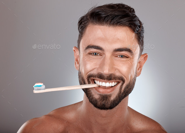 Portrait, man and toothbrush with smile, wellness and on grey studio ...