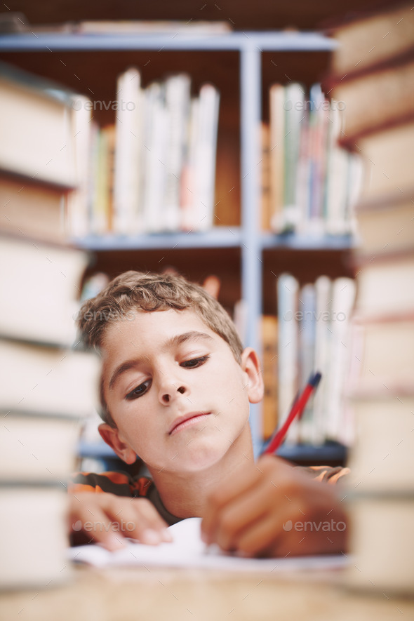 Hmmm...A young boy doing some creative writing between a stack of books ...