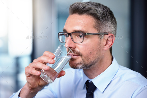 Stay hydrated throughout the day. shot of a mature businessman drinking ...