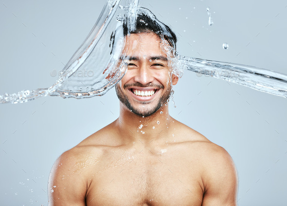 Studio portrait of a handsome young man splashing water on his face ...