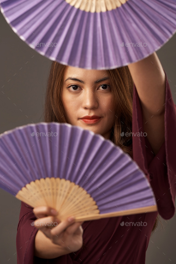 Cropped portrait of an attractive young woman posing with fans in ...