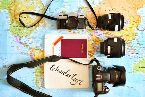 High angle shot of a map with a passport and various cameras and lenses ...